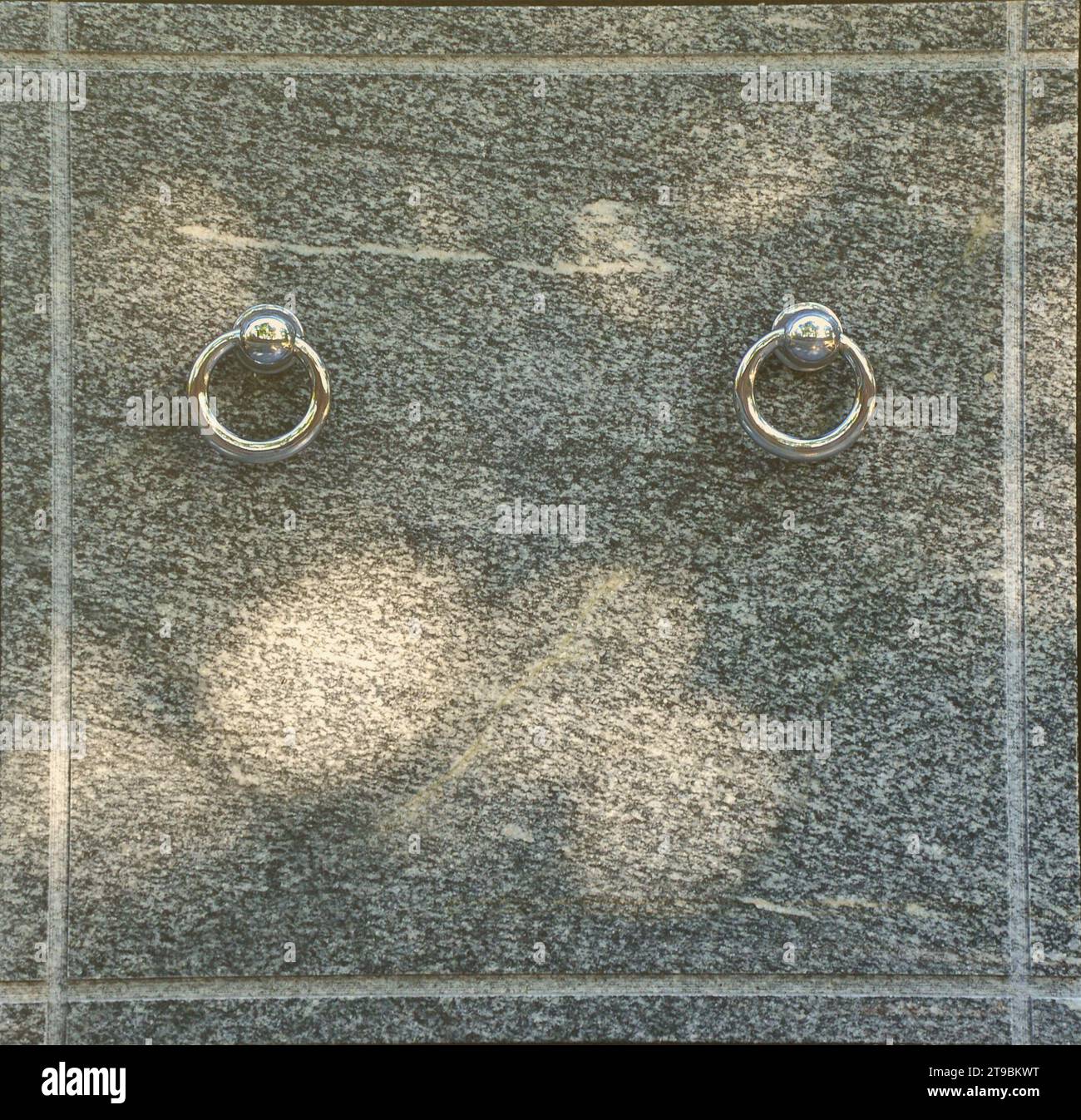 The front part of the granite crypt with metal ring handles in the ...