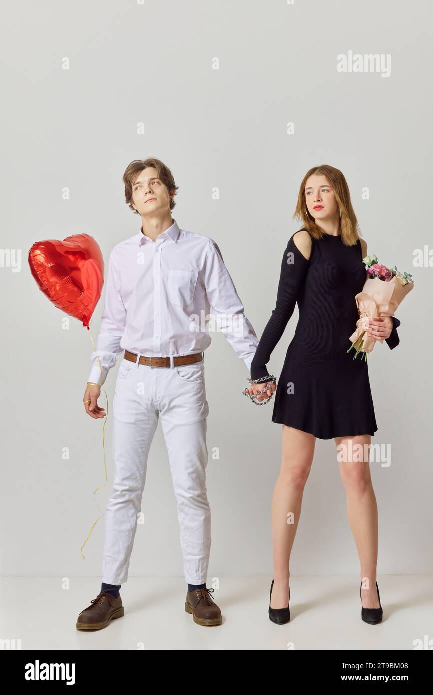 Affection. Young lovely couple connected by chains with balloons and ...