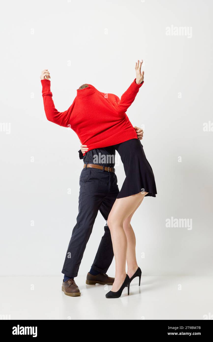 Young cute couple standing in one red sweater against white studio ...