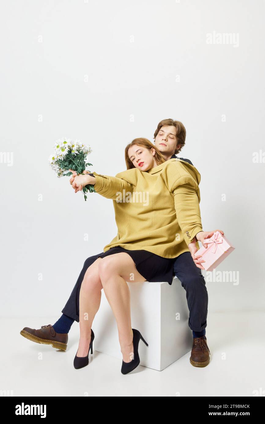 Candy-bouquet period. Couple hugs sitting on stage in one jacket with ...