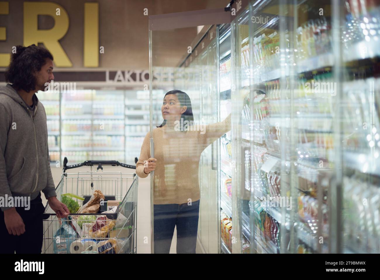 Couple standing in supermarket and talking while shopping Stock Photo ...