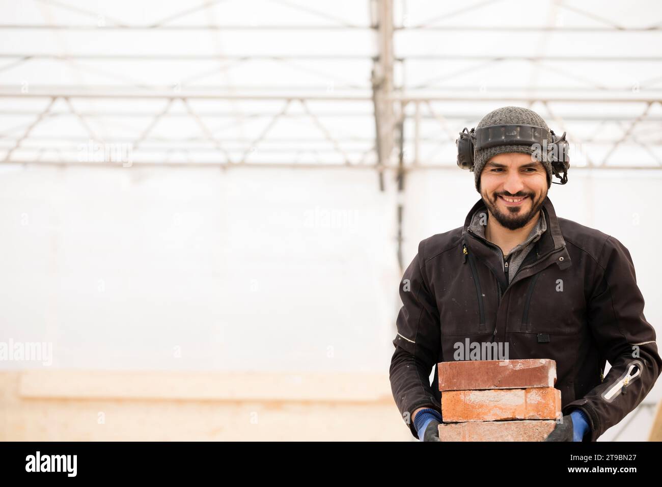 Portrait of happy male construction worker carrying bricks Stock Photo ...