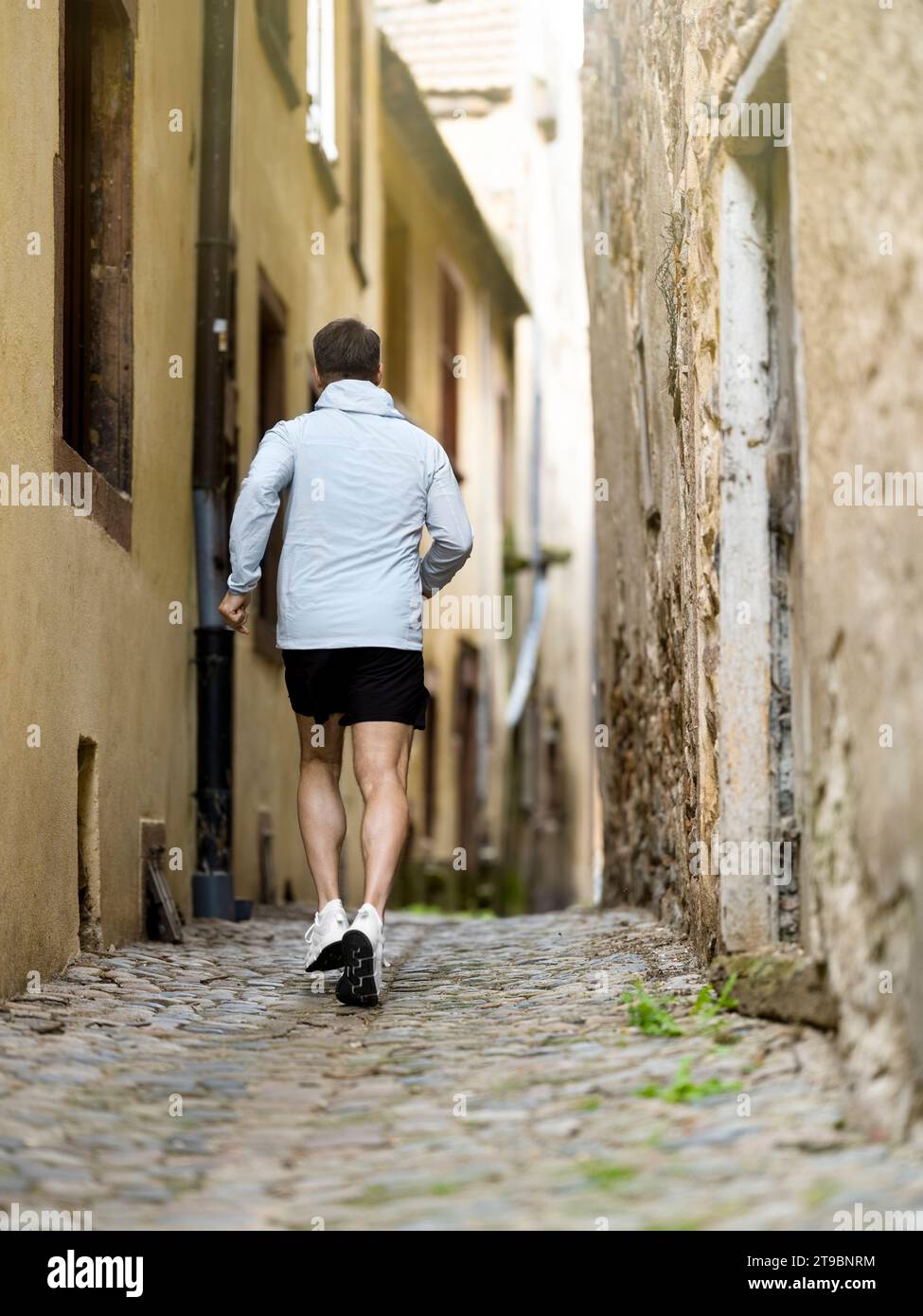 Man walking in narrow alley in old town Stock Photo - Alamy