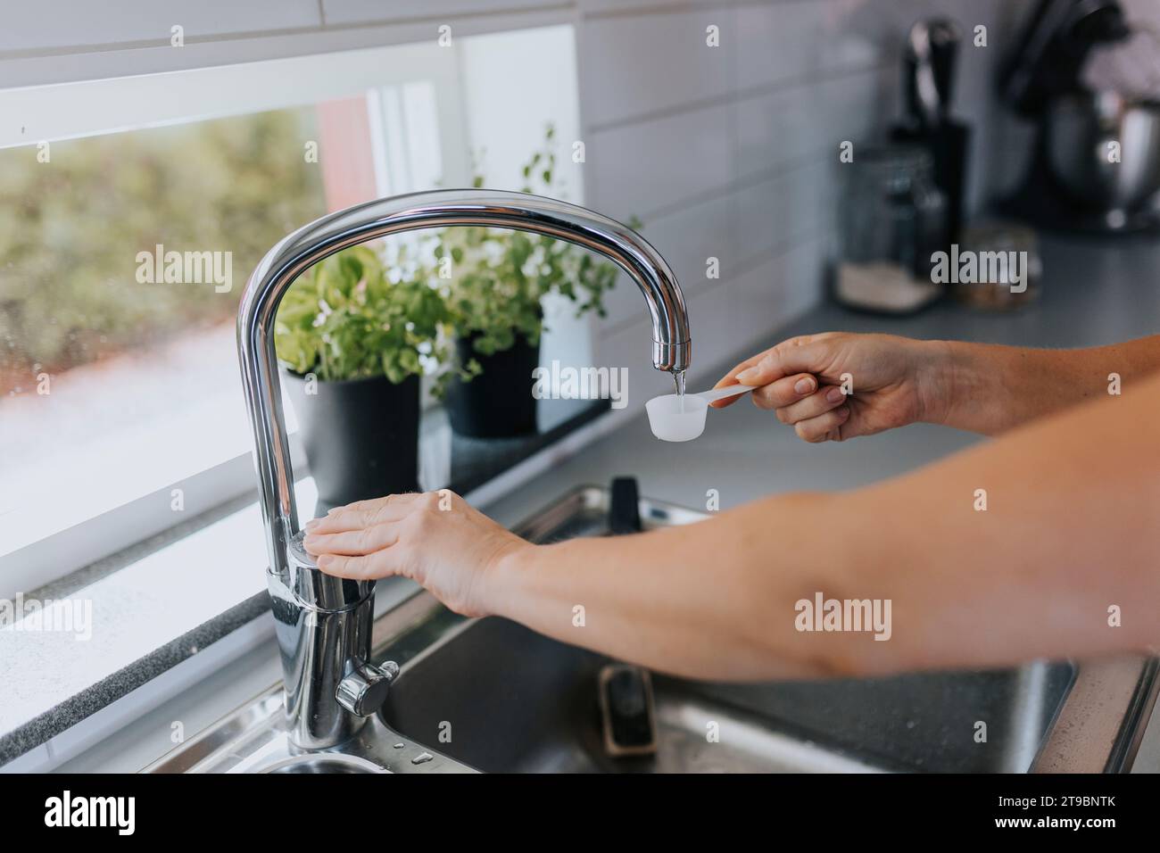 Woman's hands pouring water into measuring spoon Stock Photo - Alamy