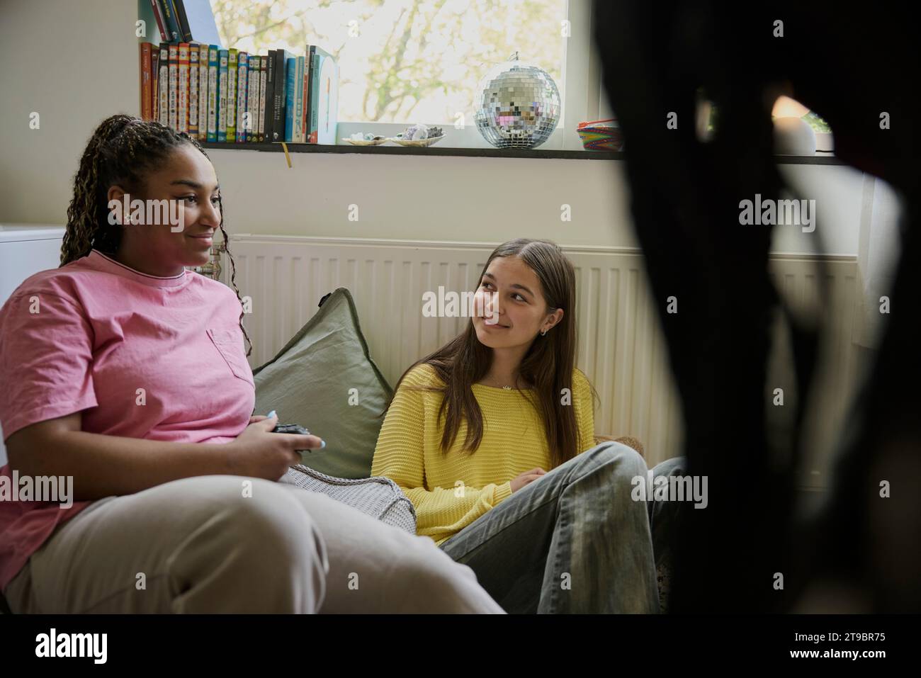 Teenage girls talking with each other while sitting at home during ...