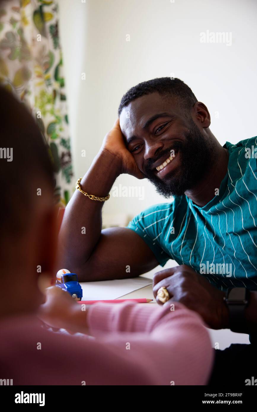 Happy man leaning on elbow while looking at daughter Stock Photo - Alamy