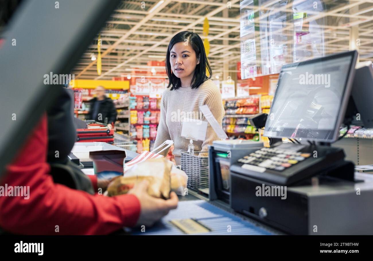 Young female customer talking to cashier at supermarket checkout Stock ...