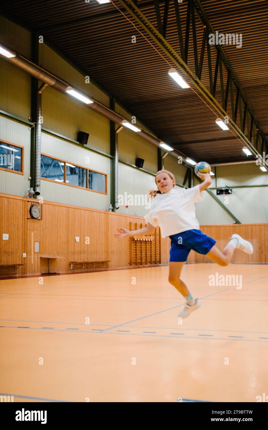 Girl jumping while throwing handball in sports court Stock Photo - Alamy