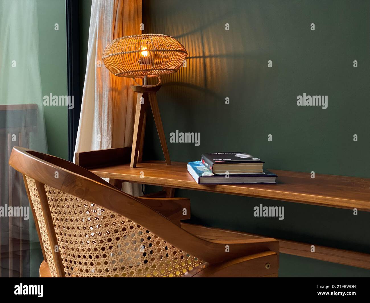 Table lamp with rattan shade on wooden table with rattan chair closeup ...