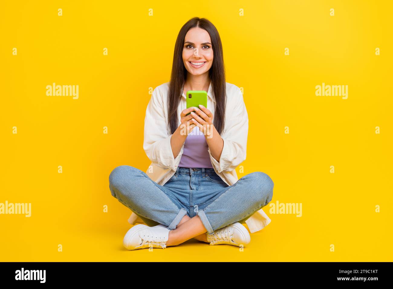 Full size portrait of cute positive girl sit floor use smart phone ...