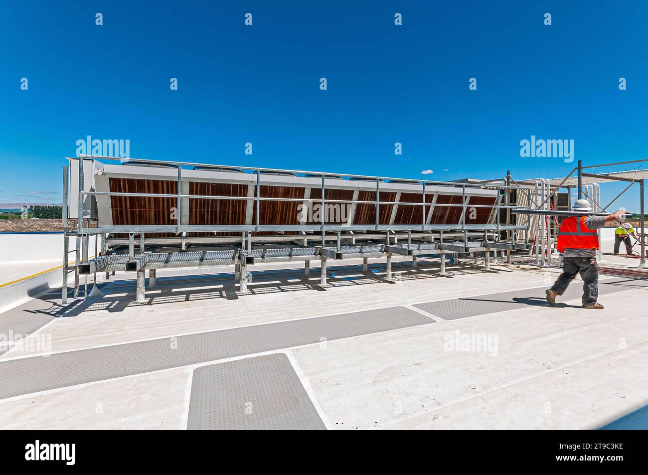 Two construction workers work near an adiabatic condenser on the roof ...