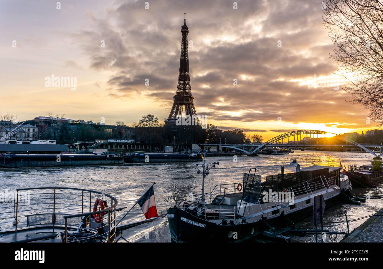 Eiffel Tower at sunset by the Seine, tourist boats with the French flag ...