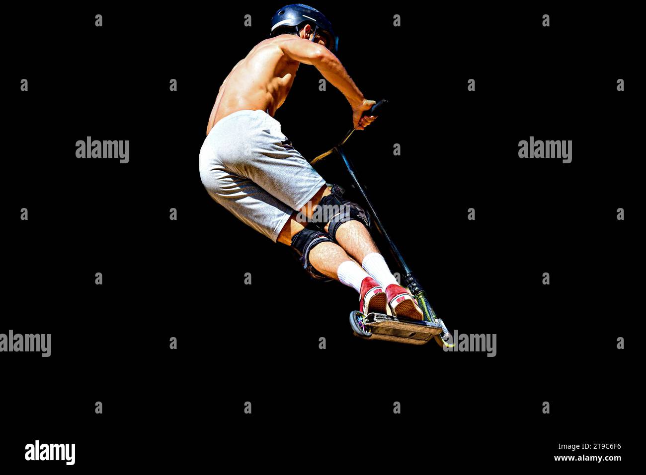 Young man practicing Scootering (Freestyle Scootering) at the SkatePark ...