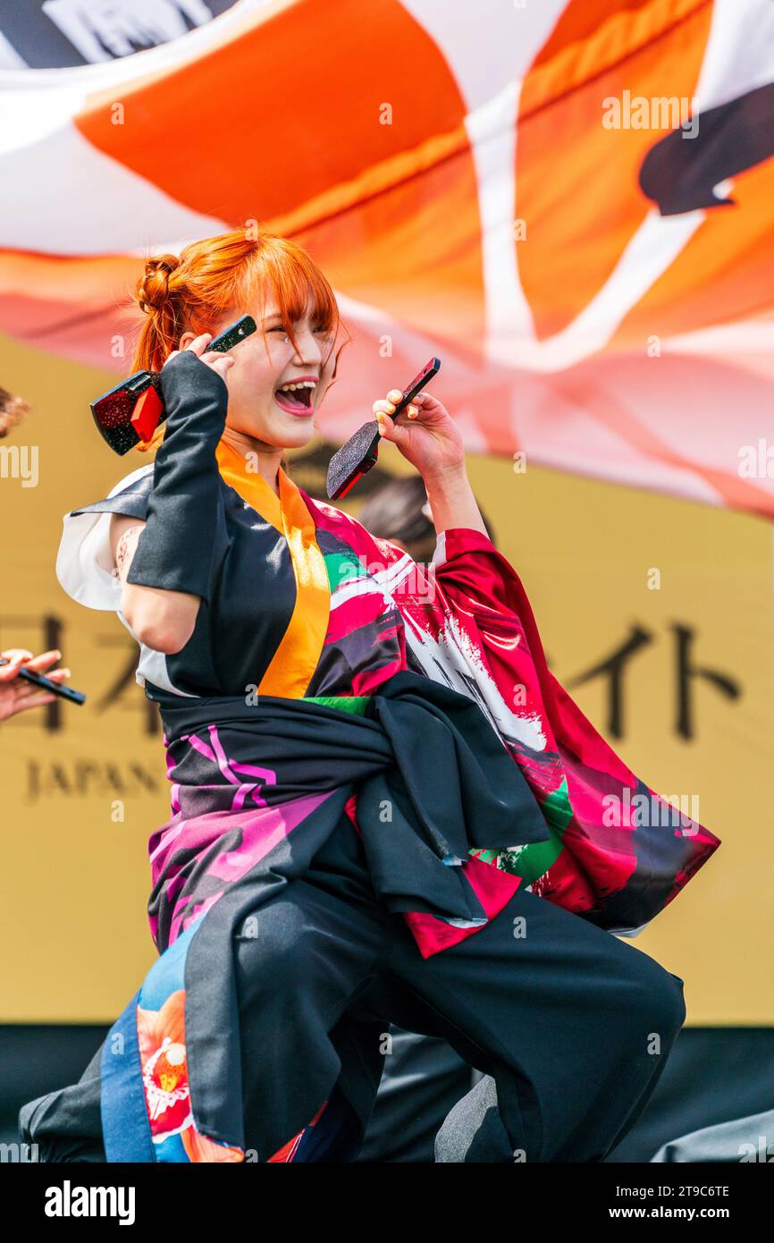 Japanese young woman red haired yosakoi dancer on stage holding naruko ...