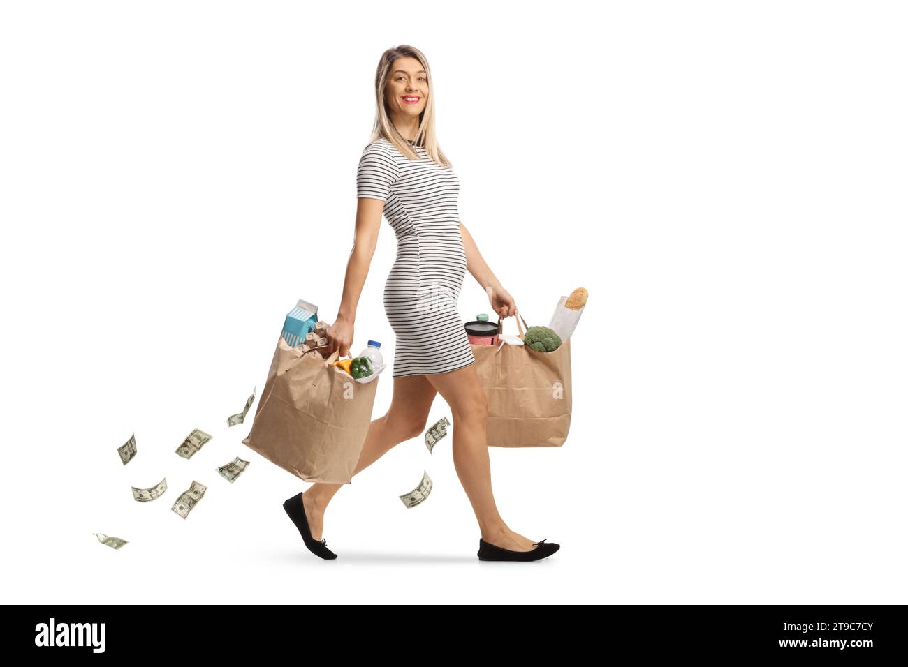 Full length shot of a young woman with grocery bags walking and losing ...