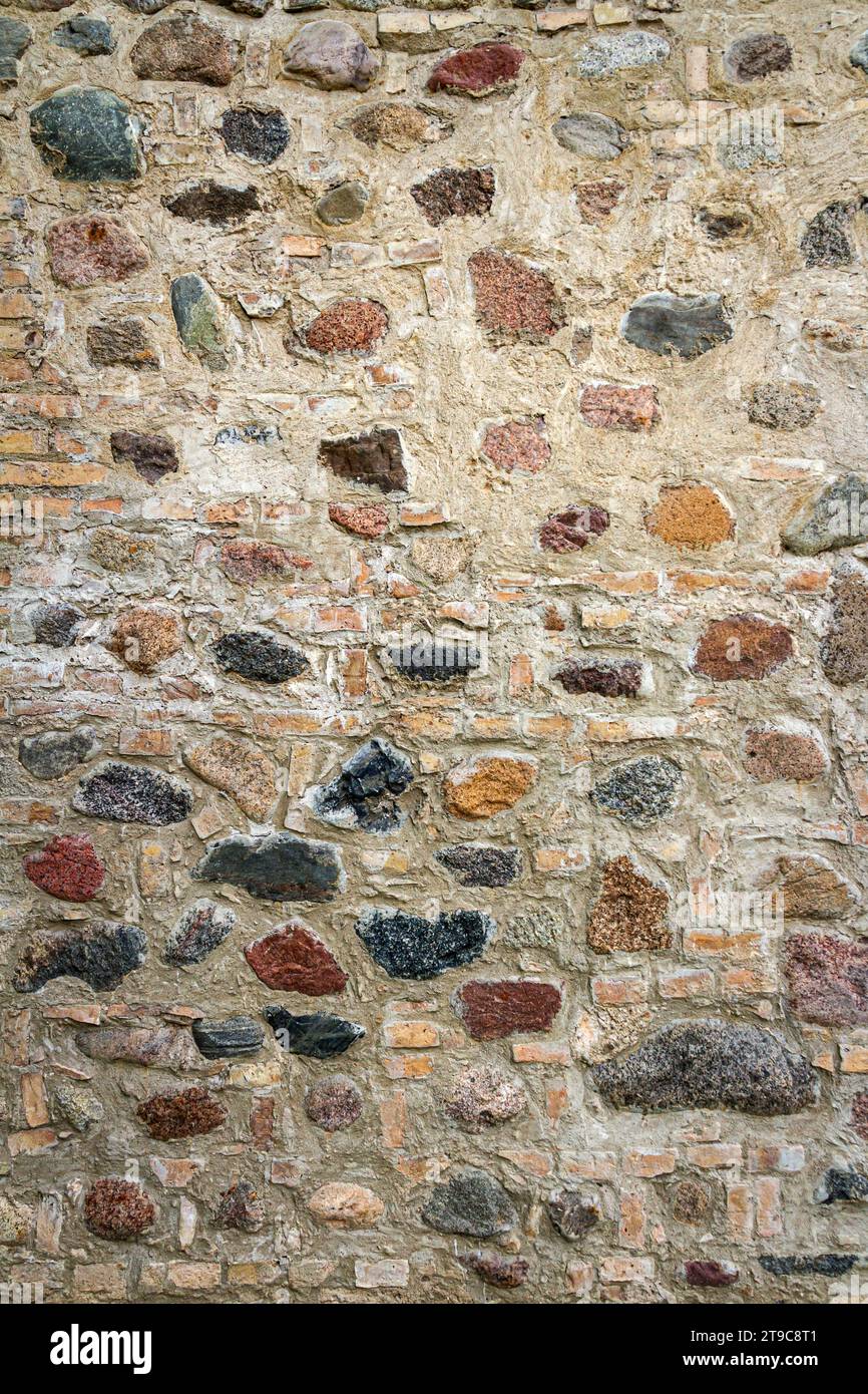 Wall texture with pieces of old bricks mixed with exposed round stones ...
