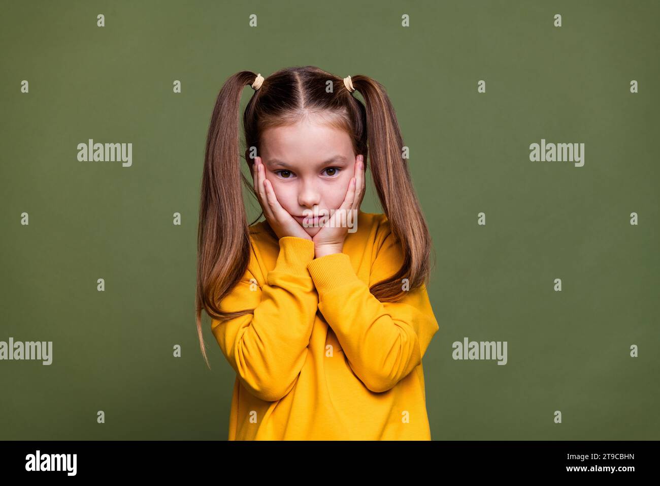 Portrait of upset small kid with tails hairstyle dressed yellow ...