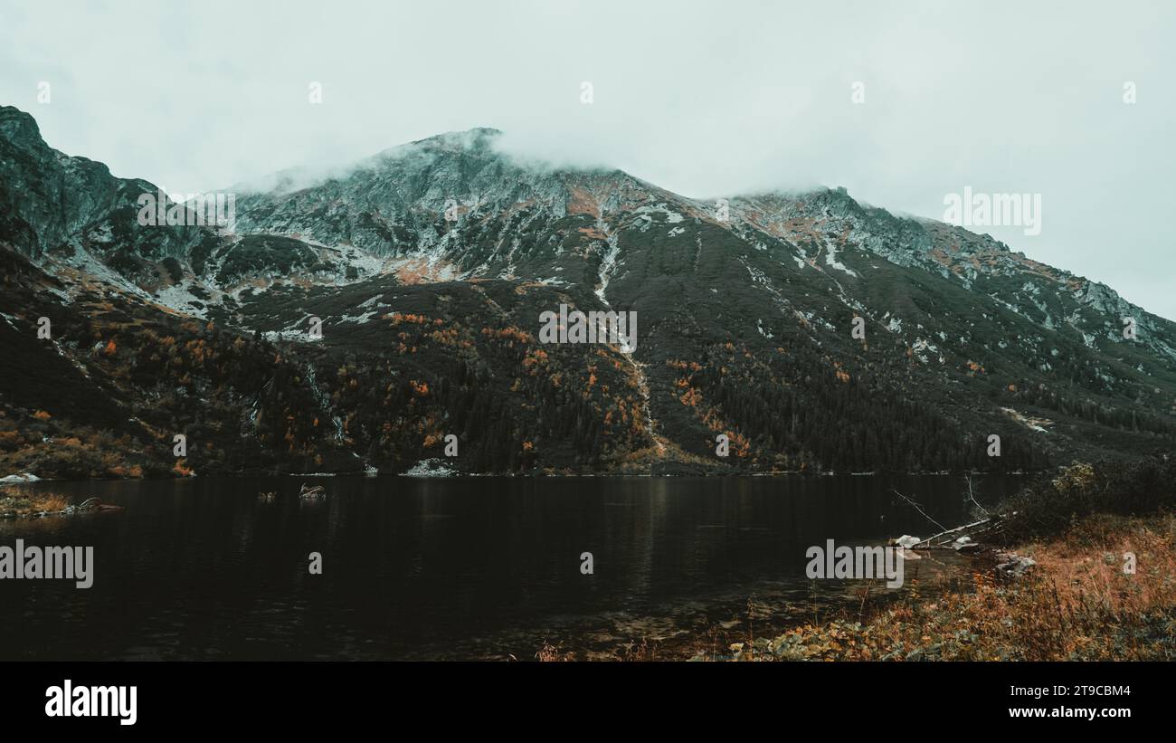 Where serenity meets grandeur, a tranquil lake embraces the towering majesty of distant ...