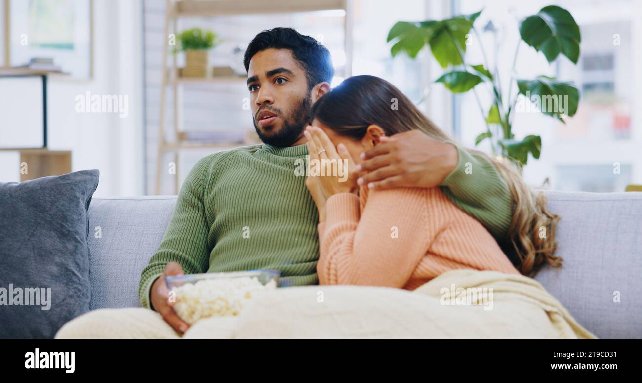 Fear, hug and couple watching tv on a sofa with popcorn for movie, film ...
