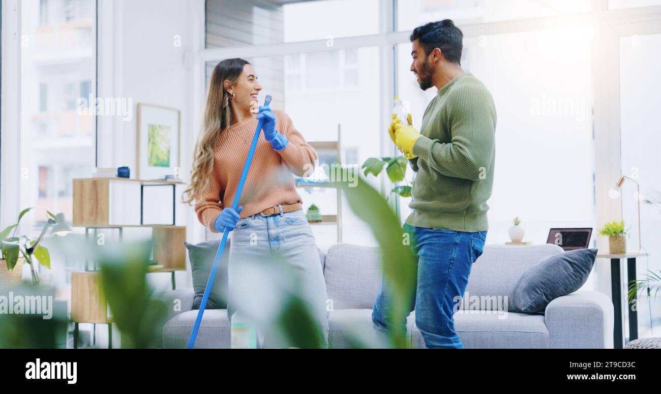 Couple, home and cleaning with singing, broom and comic performance in living room, hygiene and ...
