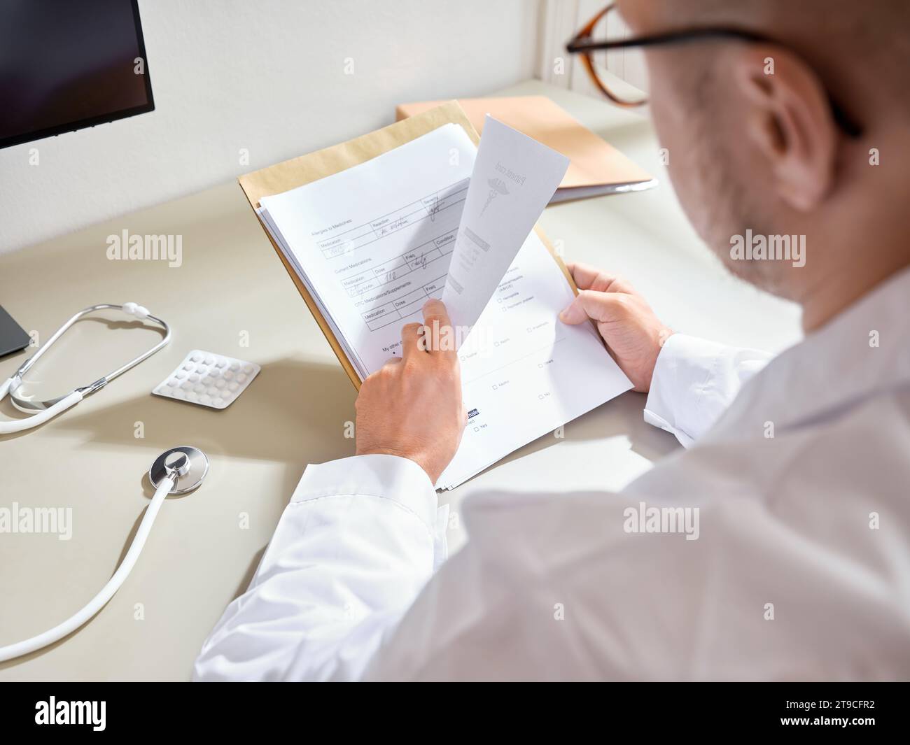 Male medical professional going through the patient's paperwork in a ...