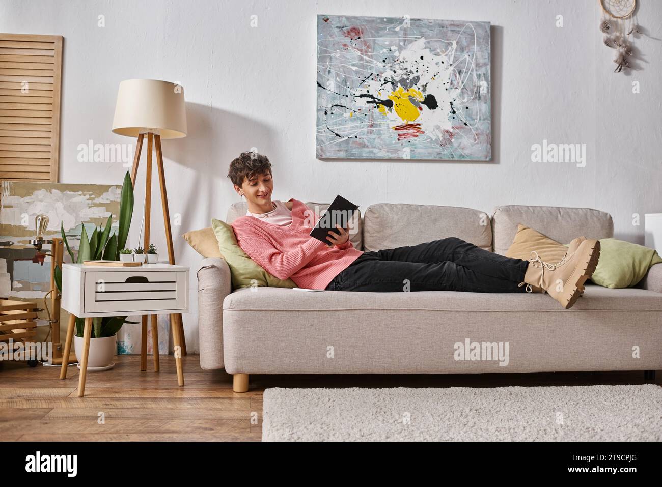 happy transgender person in pink sweater writing in notebook and ...