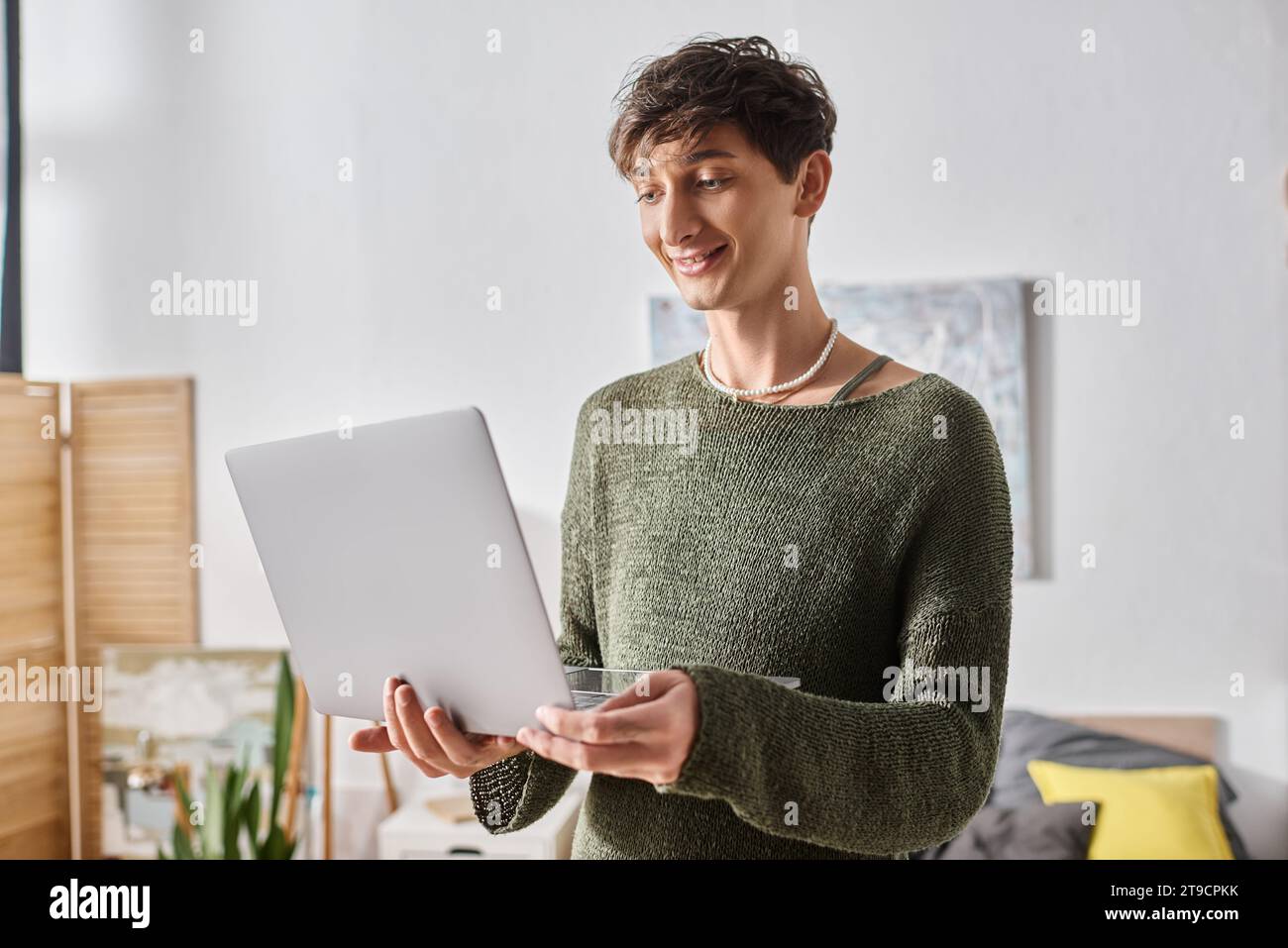 transgender blogger with curly hair using laptop while standing in ...