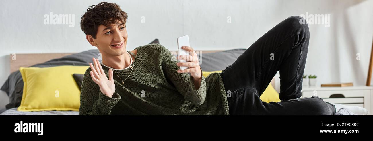 happy and curly transgender social media influencer waving hand during ...