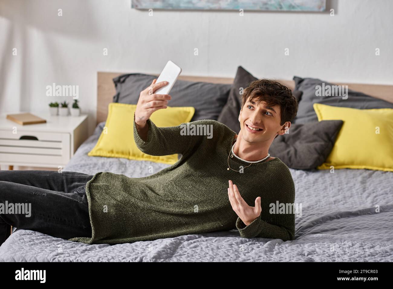 cheerful and curly transgender social media influencer taking selfie on ...