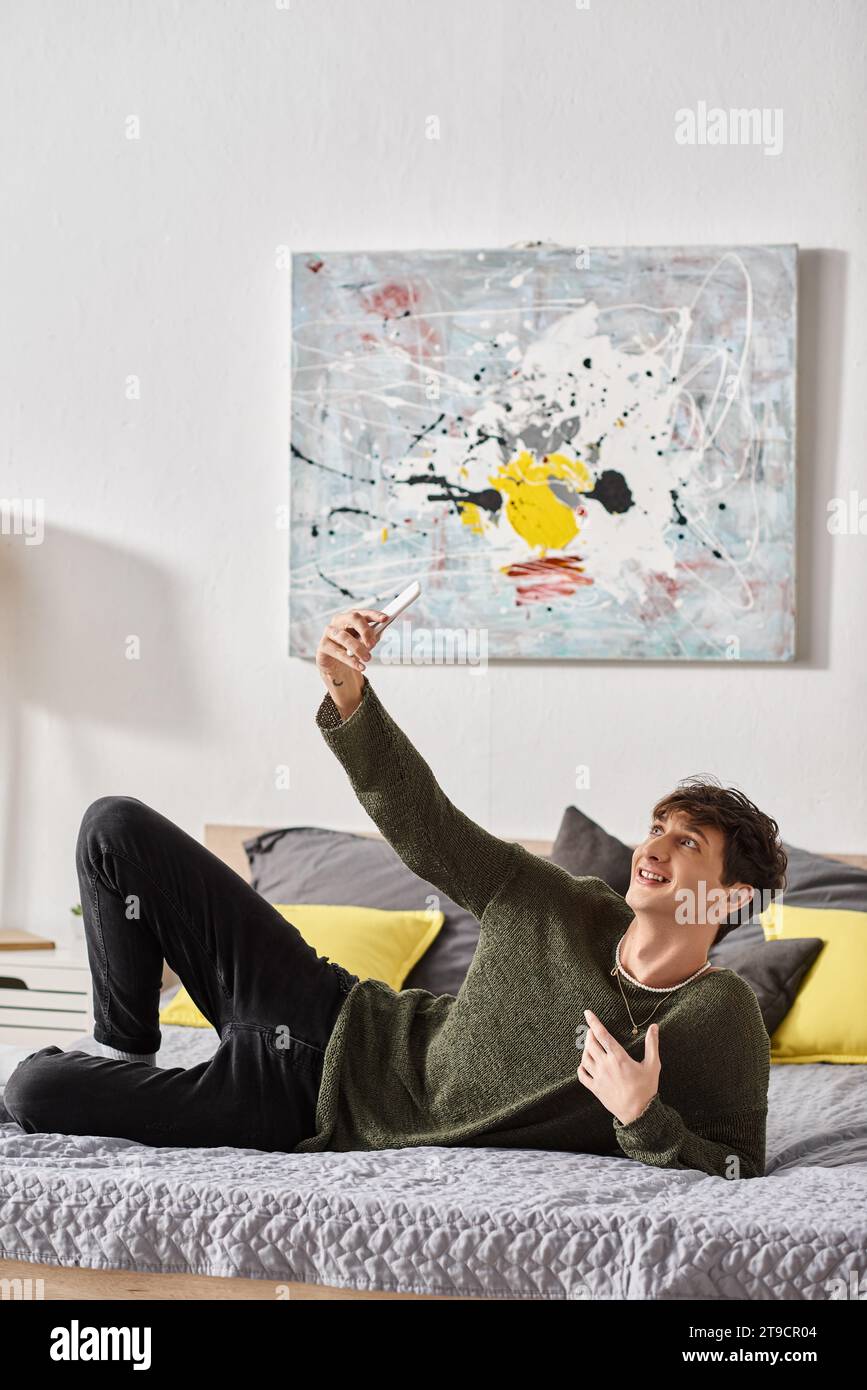 cheerful and curly transgender social media influencer taking selfie on ...