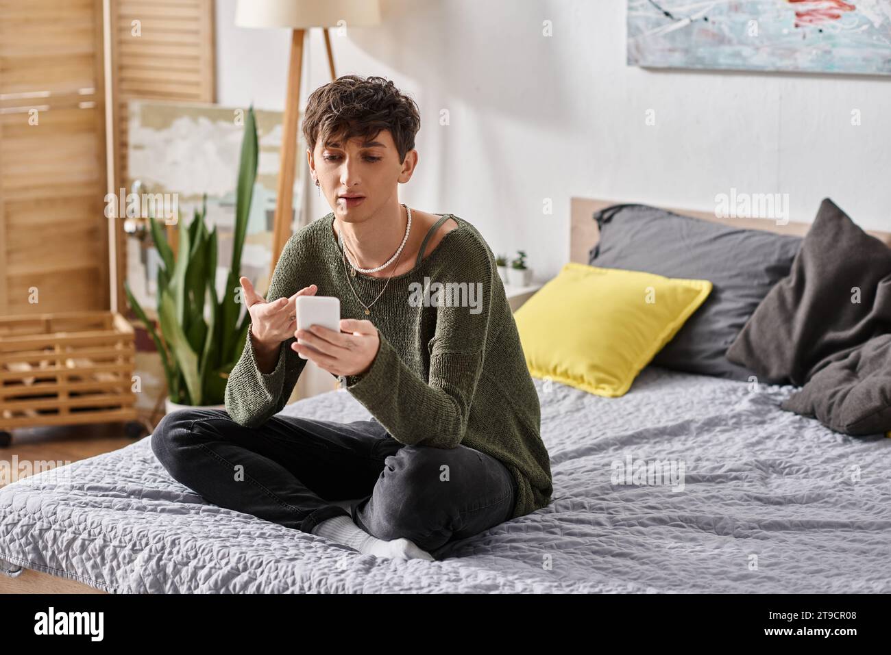 happy and curly transgender influencer using smartphone and sitting on ...