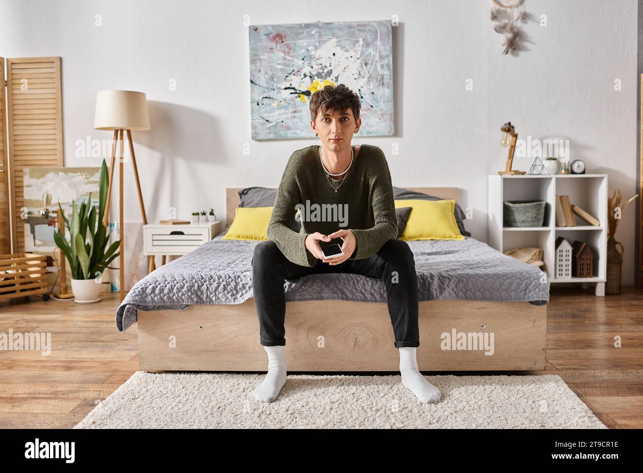 young transgender person in casual attire looking at camera and sitting ...