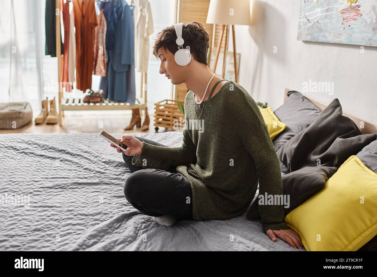 curly transgender person in wireless headphones using smartphone and ...