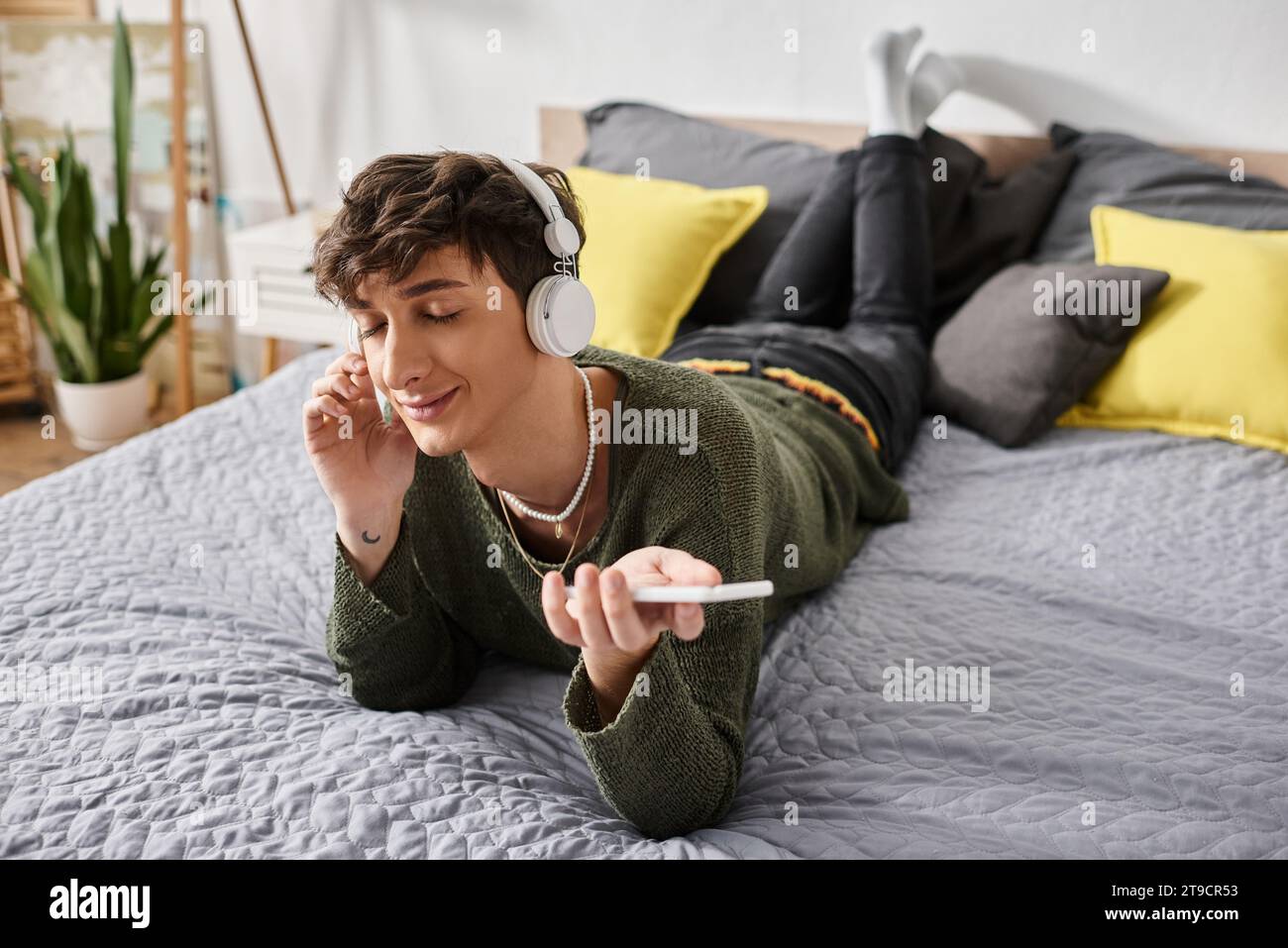 happy curly transgender person in wireless headphones holding ...