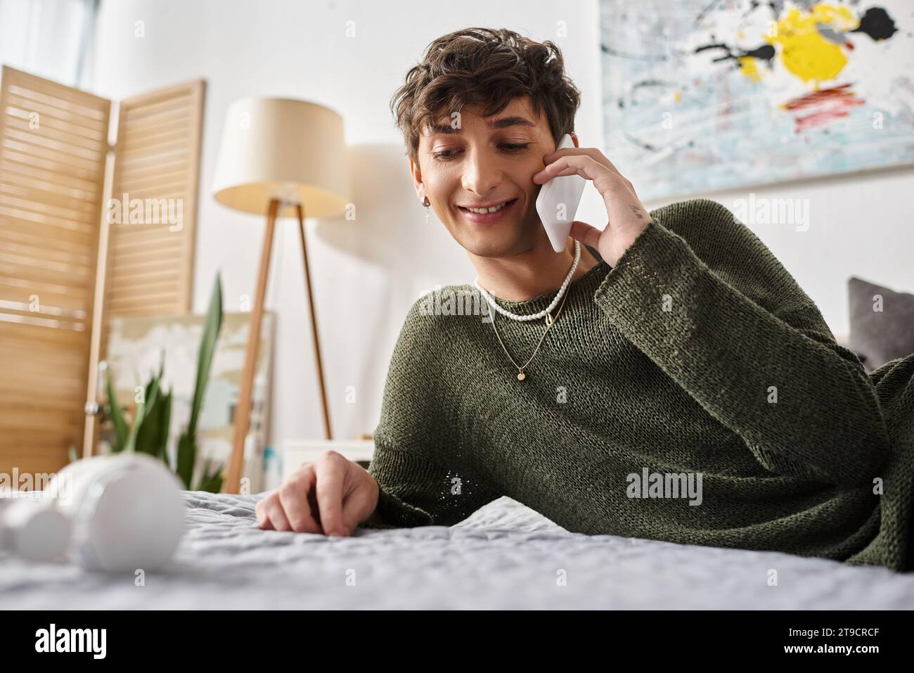 happy and curly transgender person in casual attire talking on ...