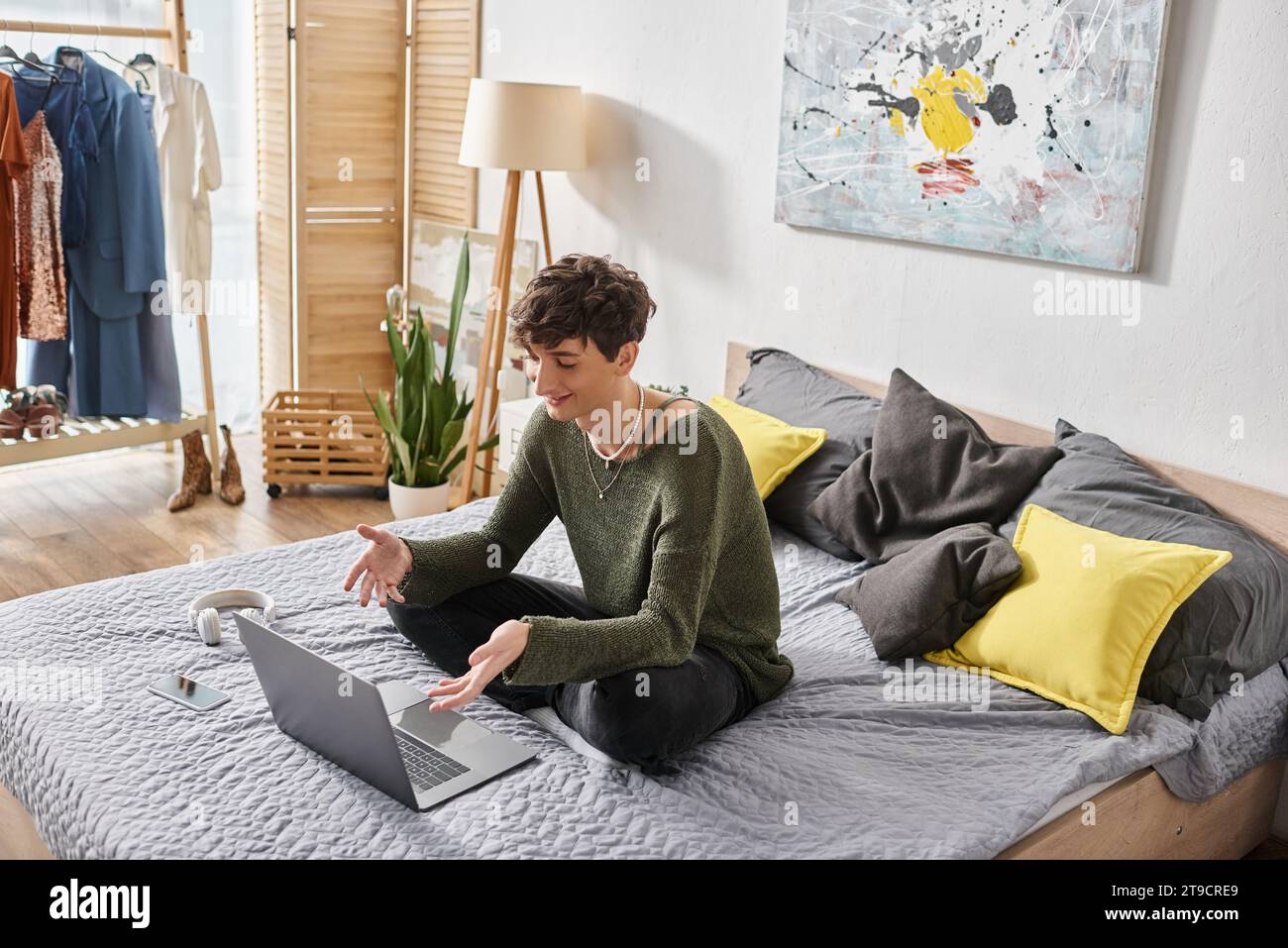 happy curly transgender blogger having video call and sitting on bed ...