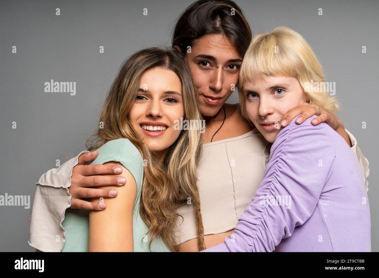 Three diverse women hugging and smiling in a studio setting, portraying ...