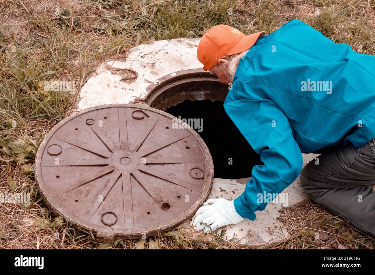 A worker leaned over the well to check the water meter. Plumbing work ...