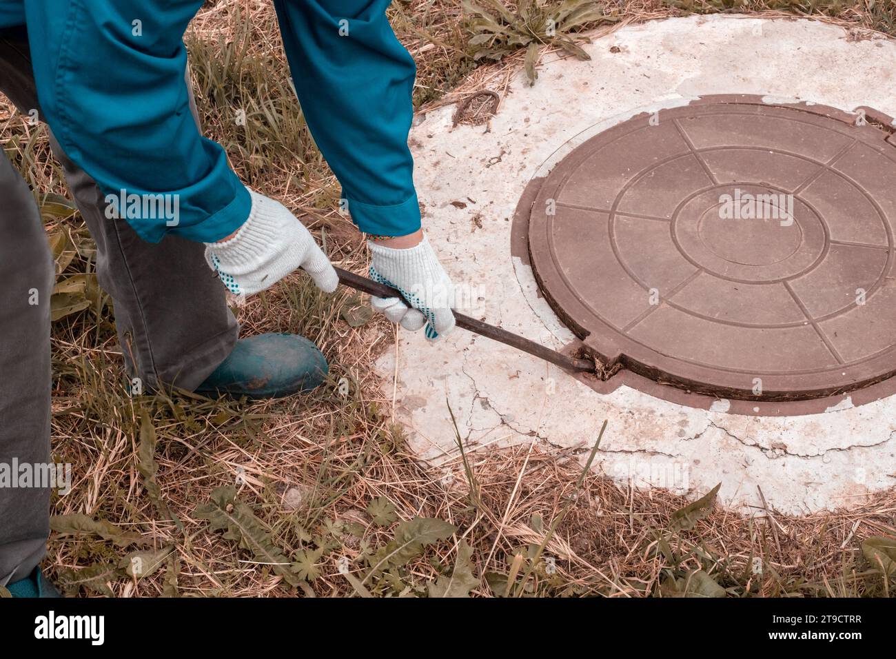 A worker opens a well hatch with a pry bar. Troubleshooting, checking ...