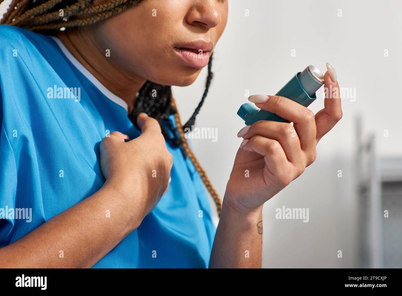 young ill african american patient using her asthma inhaler in hospital ...