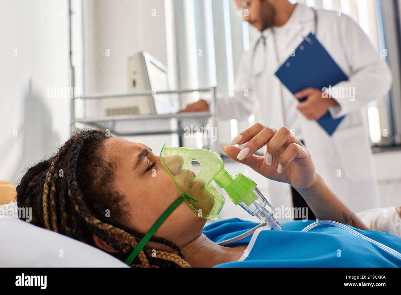 focus on african american woman lying in bed with oxygen mask with ...