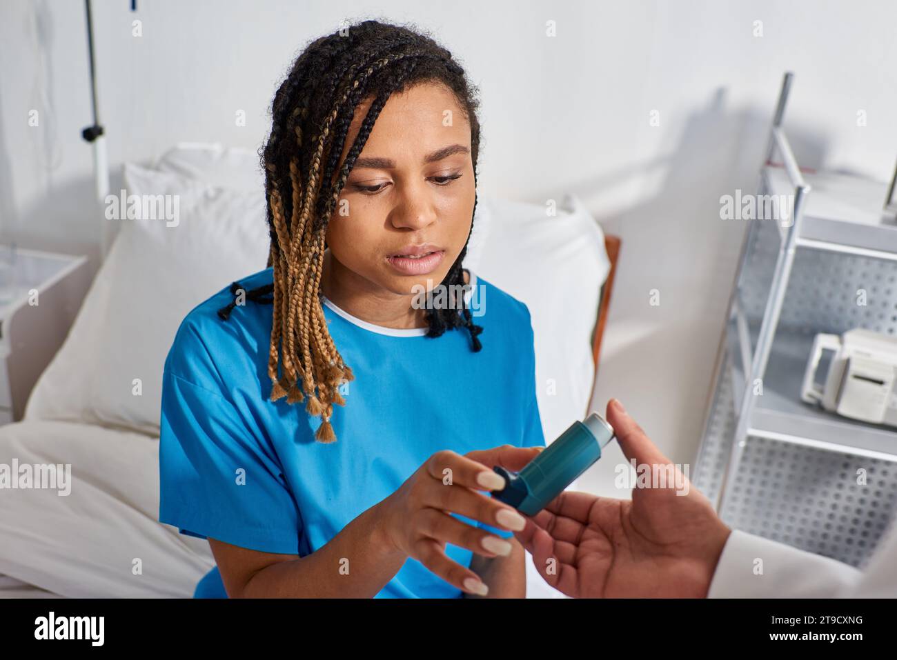 ill african american patient in hospital ward taking inhaler from her ...