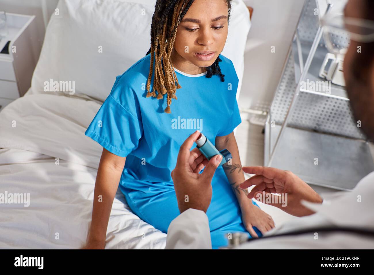 ill african american patient in hospital ward taking inhaler from her ...