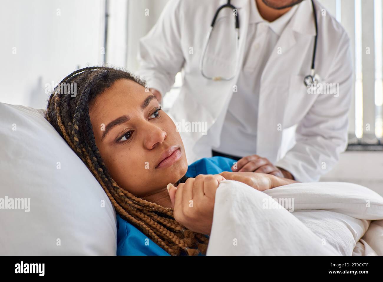 cropped view of indian doctor comforting his ill sad african american ...