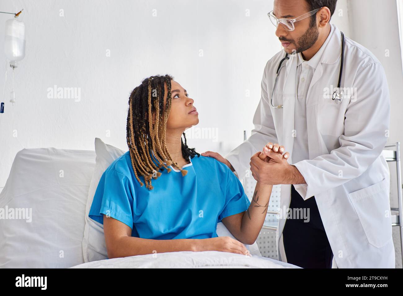 serious indian doctor comforting his african american sad patient in ...