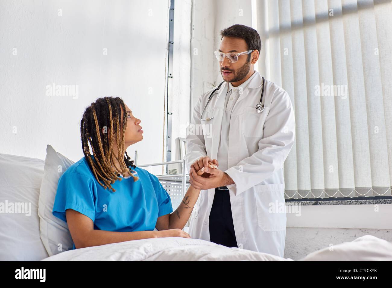 serious indian doctor comforting his african american sad patient in ...