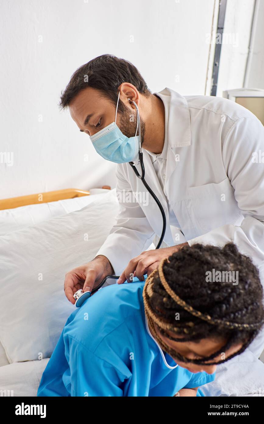 young indian doctor examining breath of ill african american patient ...