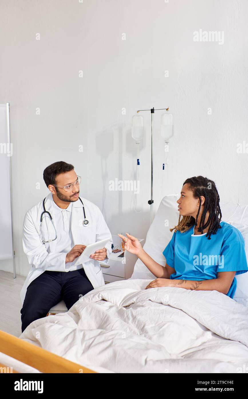 african american patient lying in hospital bed talking to her indian ...
