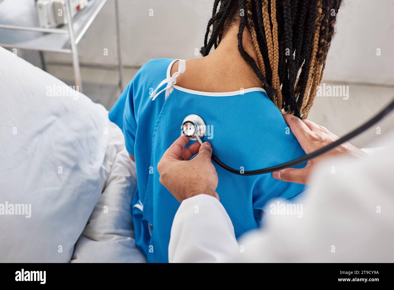 back view of indian doctor checking breath of his african american ...