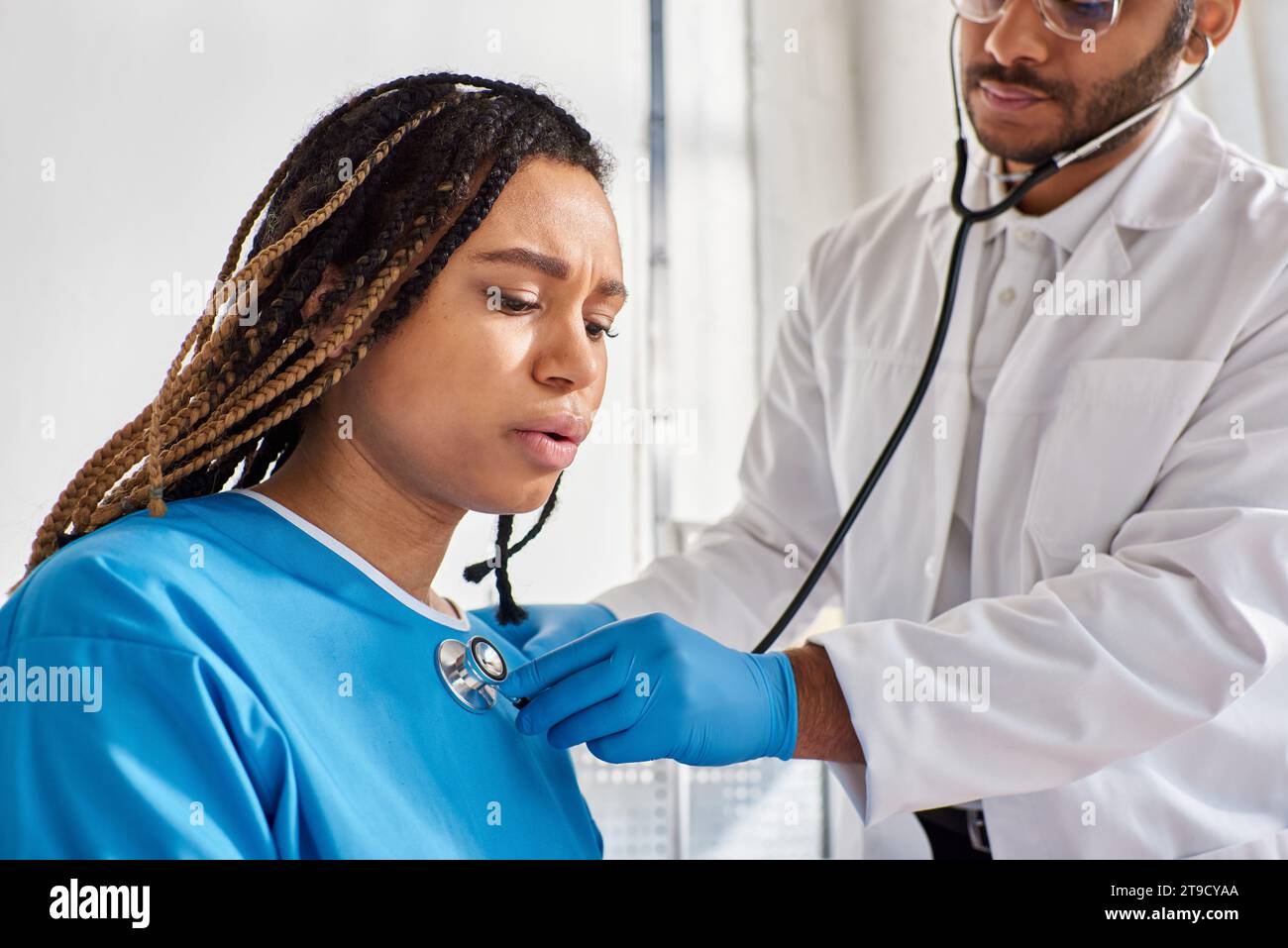 indian doctor checking breath of his african american female patient in ...